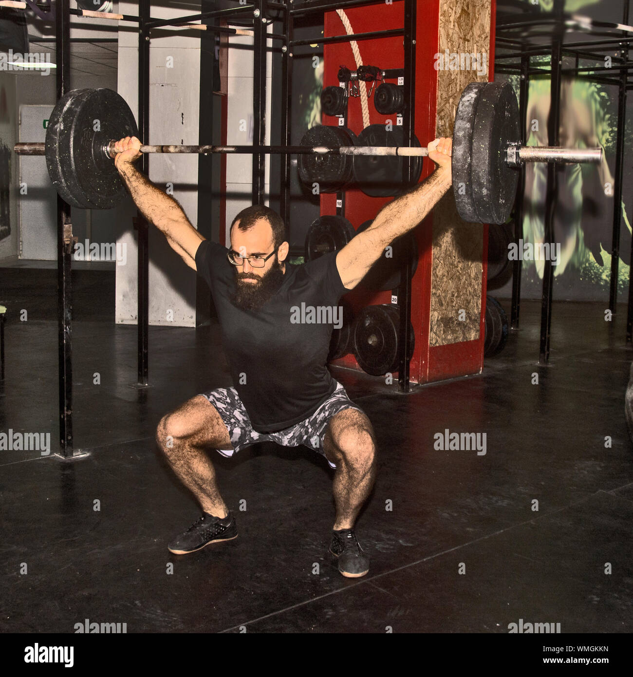 A strong and young man exercises weight lifting to strengthen the body ...