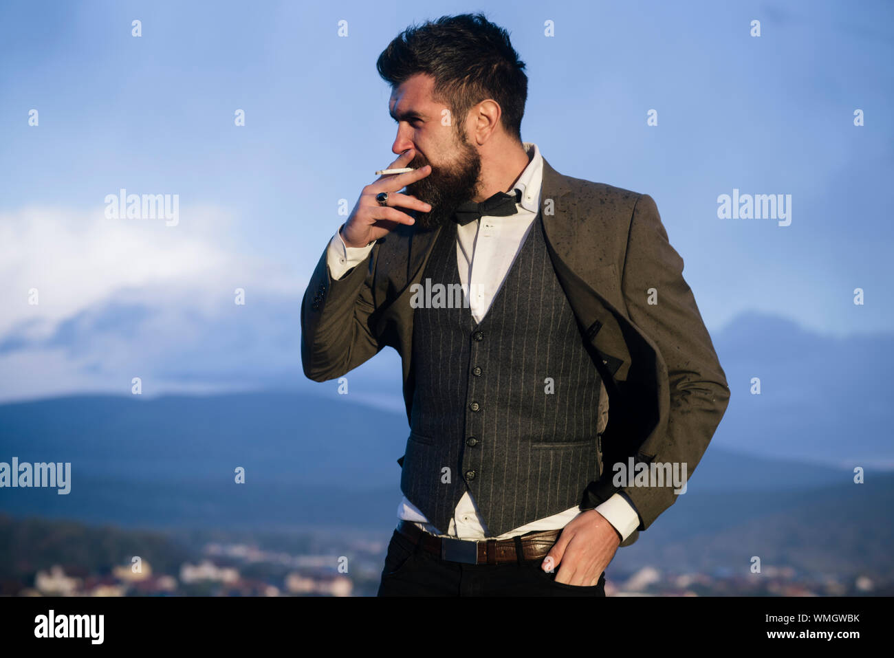 Fashion man smoking on mountain landscape. Fashion smoker with ...
