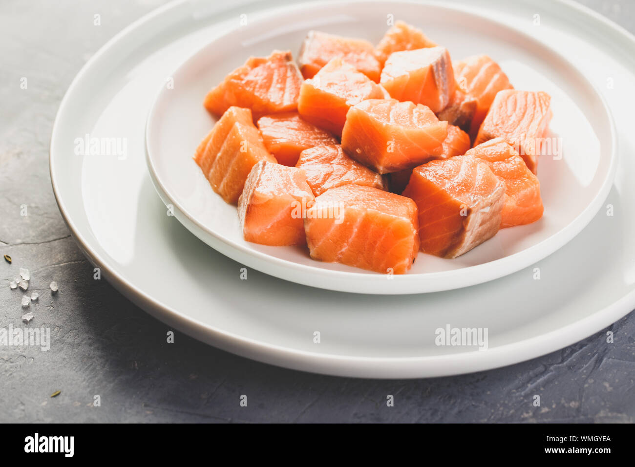 Diced pieces of salmon for marinating on white plate Stock Photo - Alamy