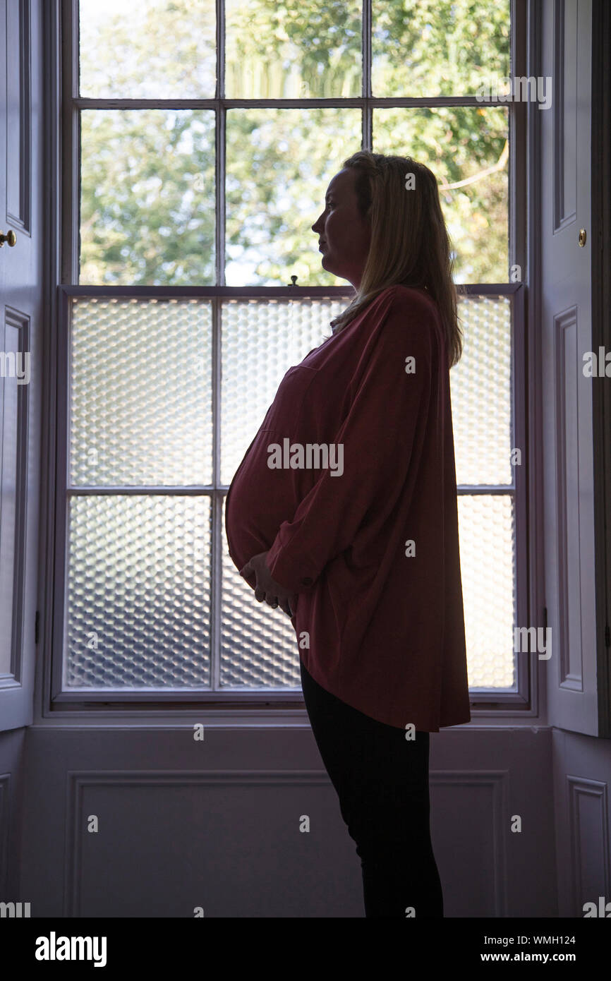 Silhouette of a prgnant woman standing infront of a window Stock Photo ...