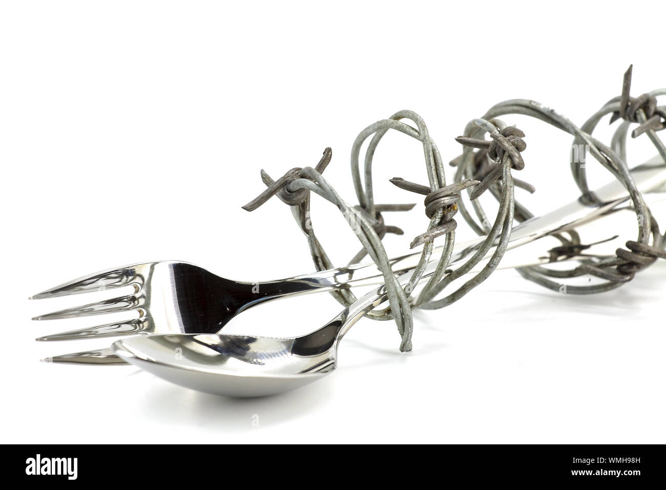 Barbed wire around fork and spoon on white background Stock Photo - Alamy