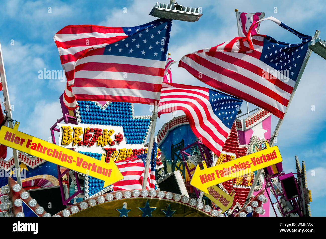 Flags of the USA at a ticket shop in front of an amusement ride on a ...
