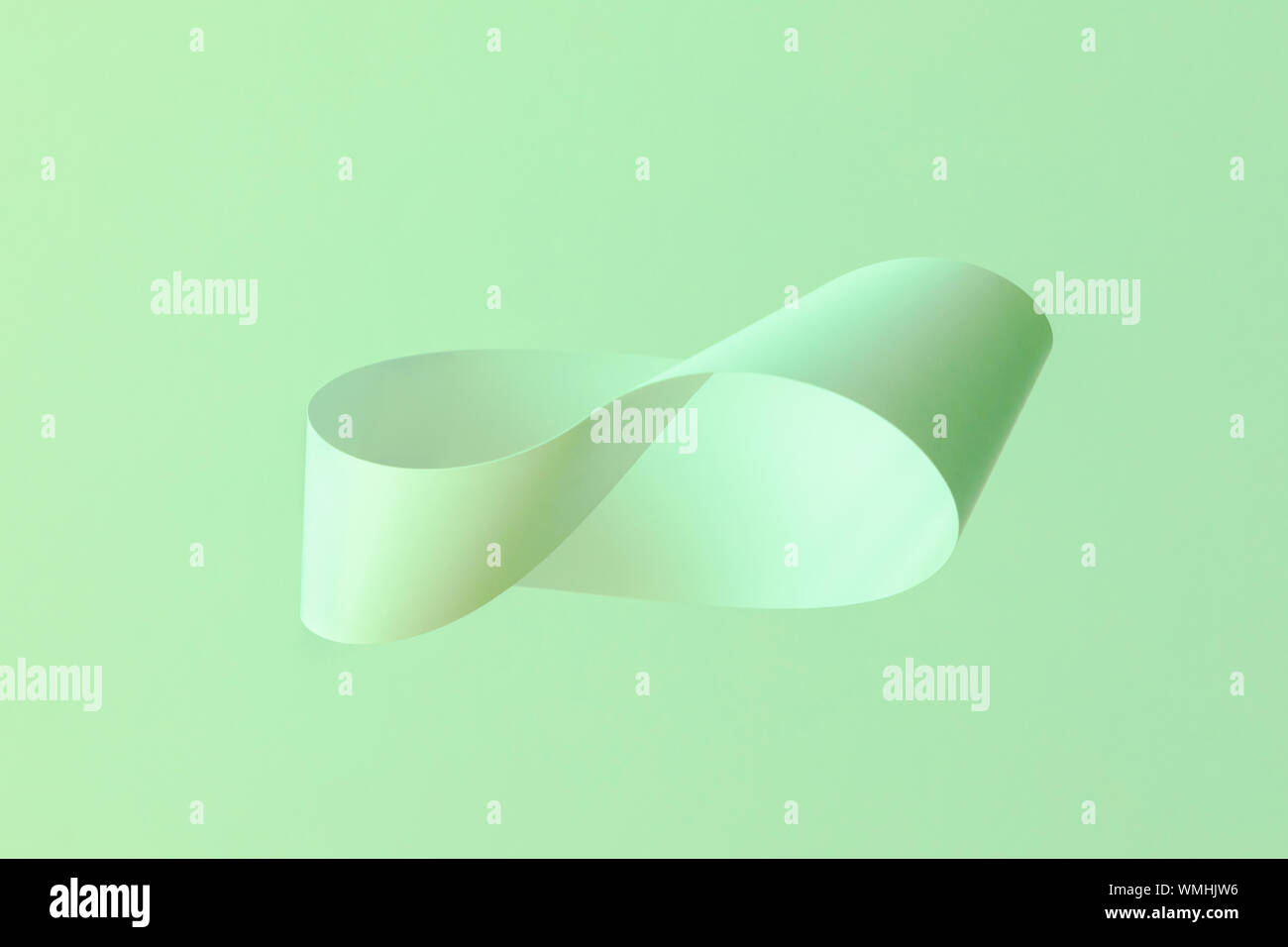 Mobius strip made from paper soaring in the air on mint background ...