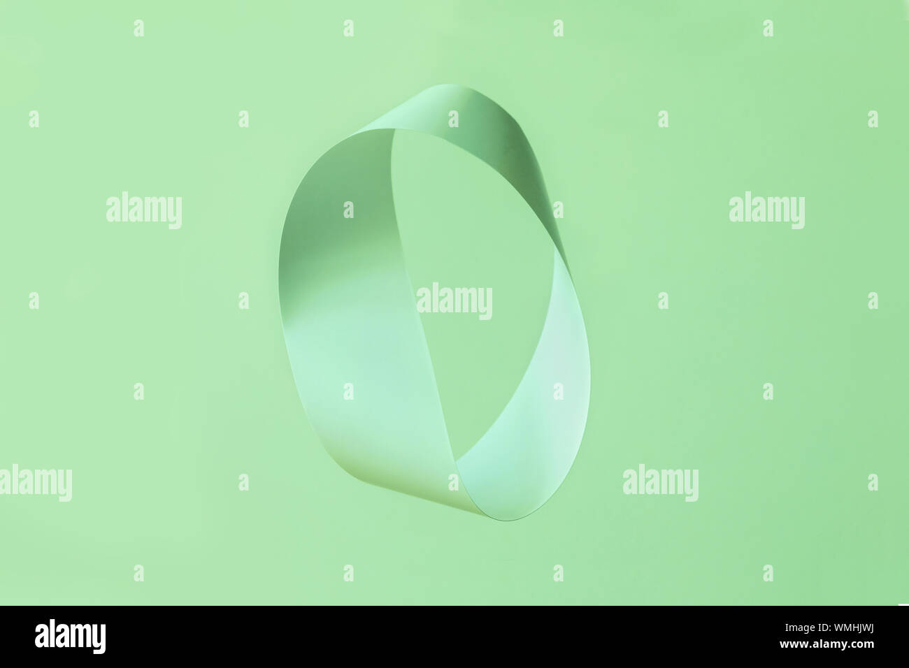 Mobius strip made from paper soaring in the air on mint background ...