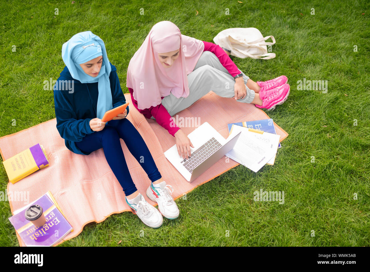 Muslim students sitting outside near university and studying Stock ...