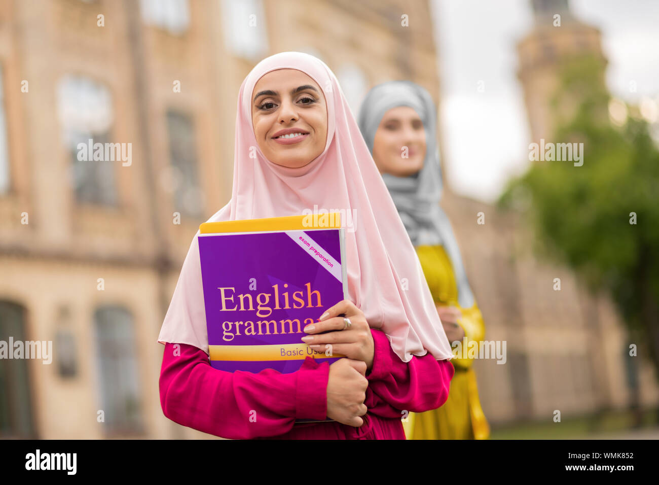Beautiful muslim student wearing pink hijab holding book Stock Photo ...