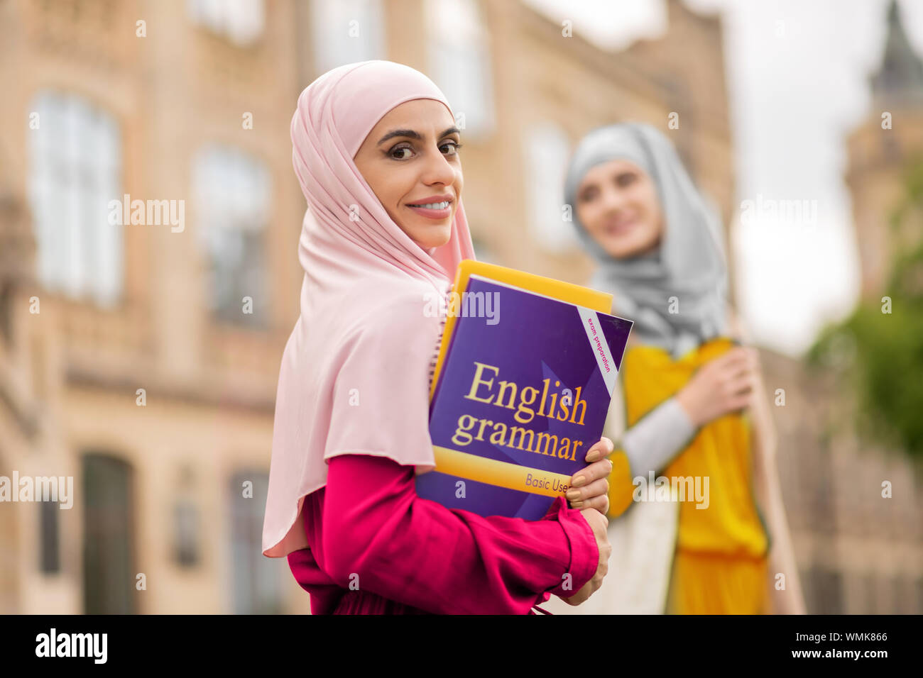Dark-eyed muslim student holding English grammar book Stock Photo - Alamy