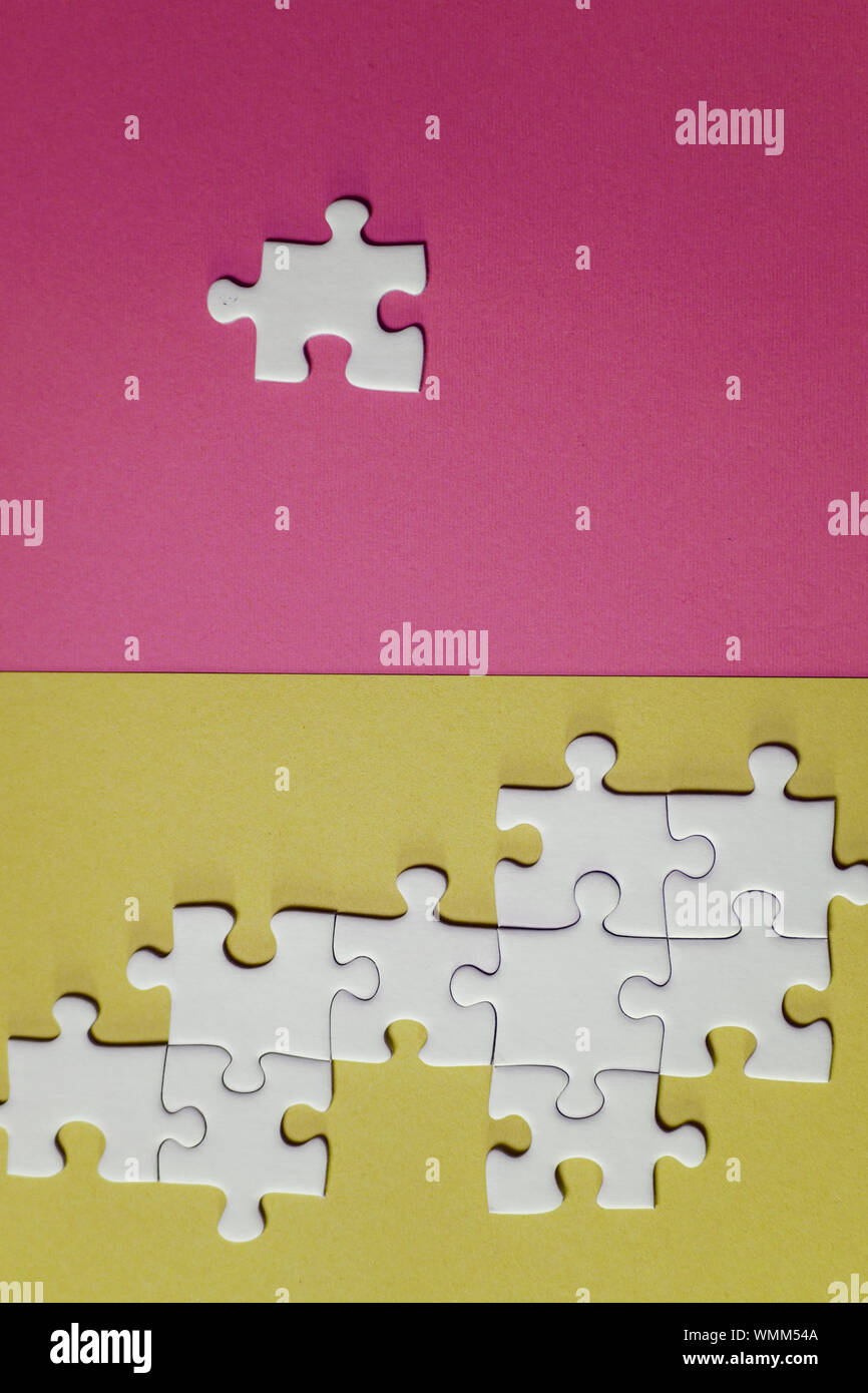 Fragment of a folded white jigsaw puzzle and a pile of uncombed puzzle ...
