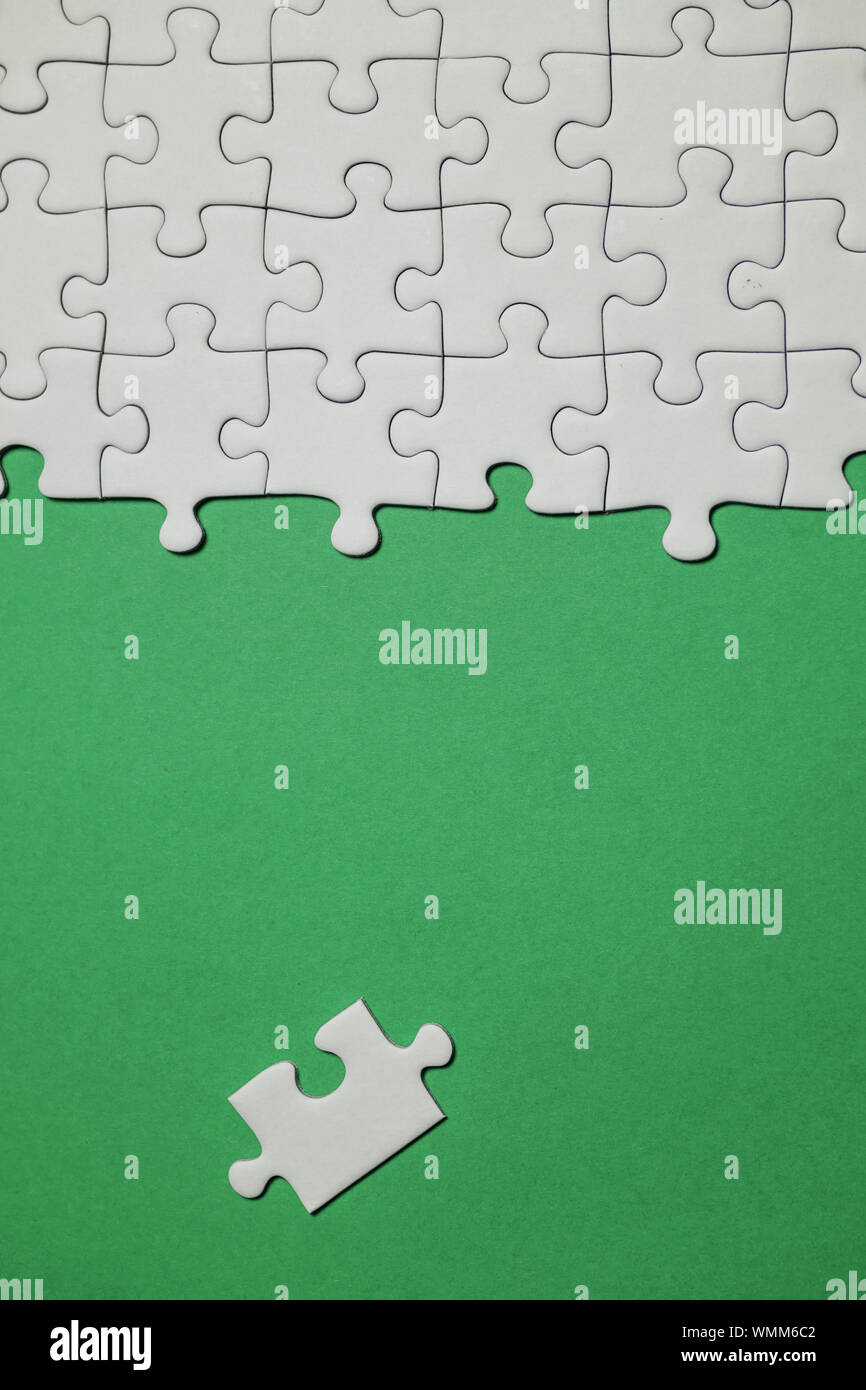 Fragment of a folded white jigsaw puzzle and a pile of uncombed puzzle ...
