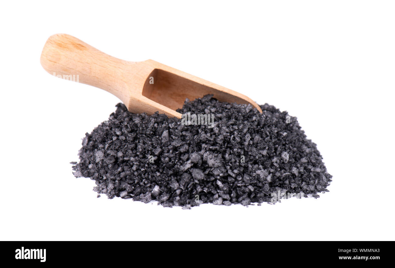 Black sea salt in a wooden spoon, isolated on white background ...