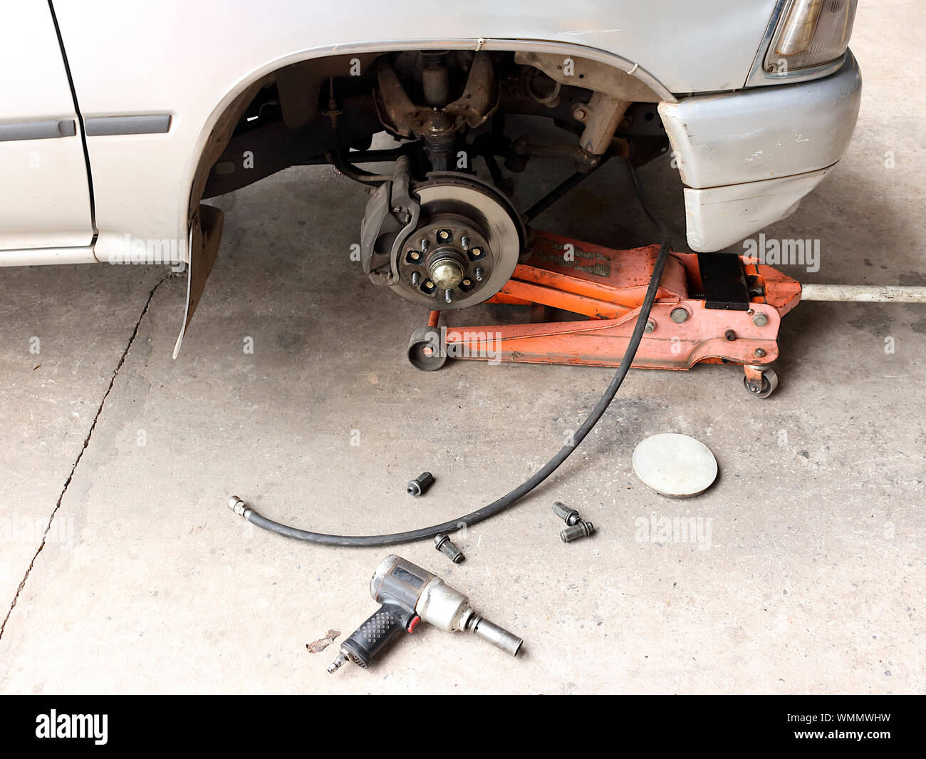 A gray car with its front right wheel removed, revealing the brake ...