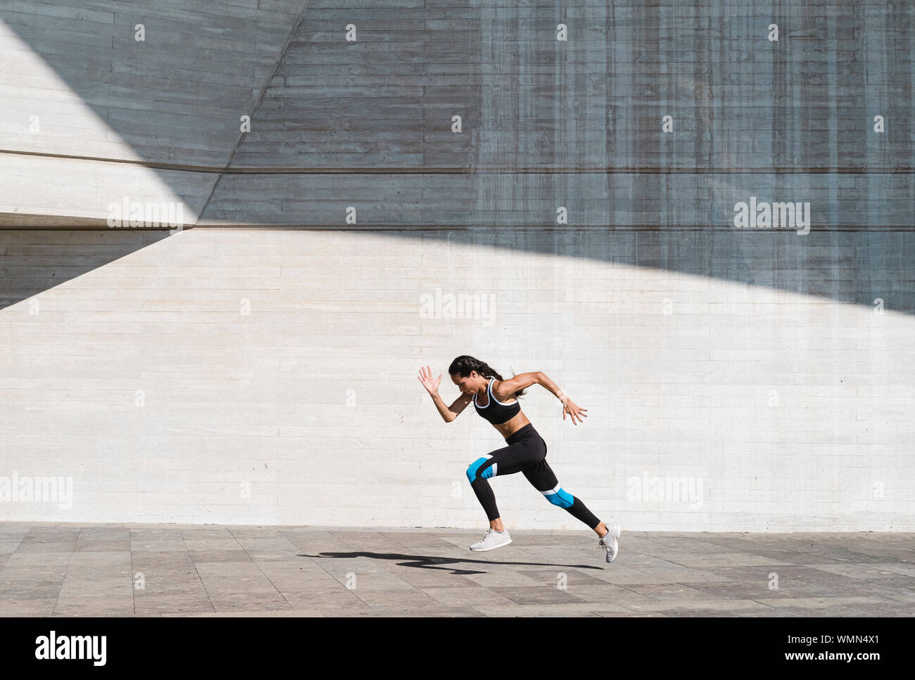 Pulled back view of female athlete running on concrete vertical Stock ...