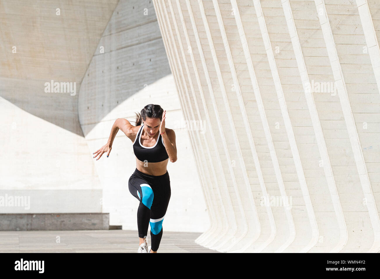 Upper body of female athlete in sportswear running fast on concrete ...