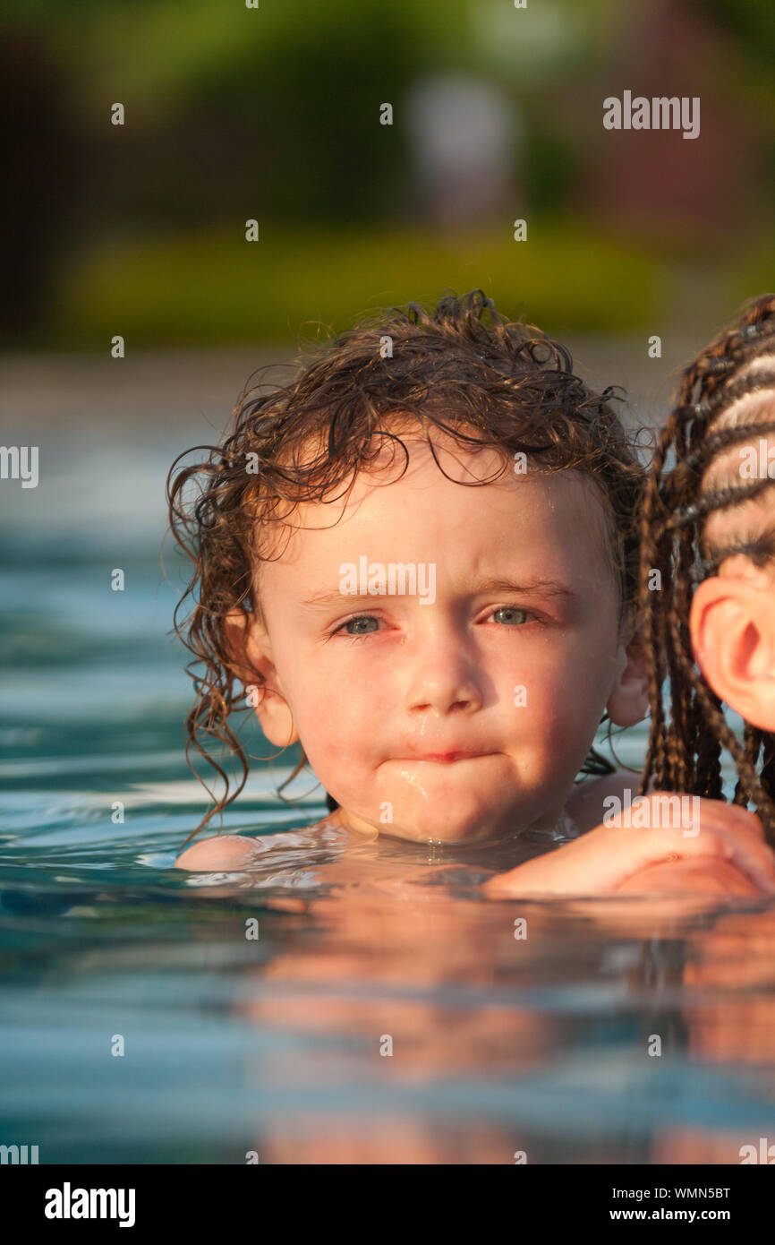 Little boy getting a piggyback ride from older girl while swimming in a ...