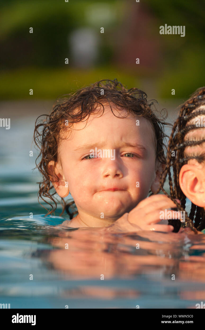 Little boy getting a piggyback ride from older girl while swimming in a ...