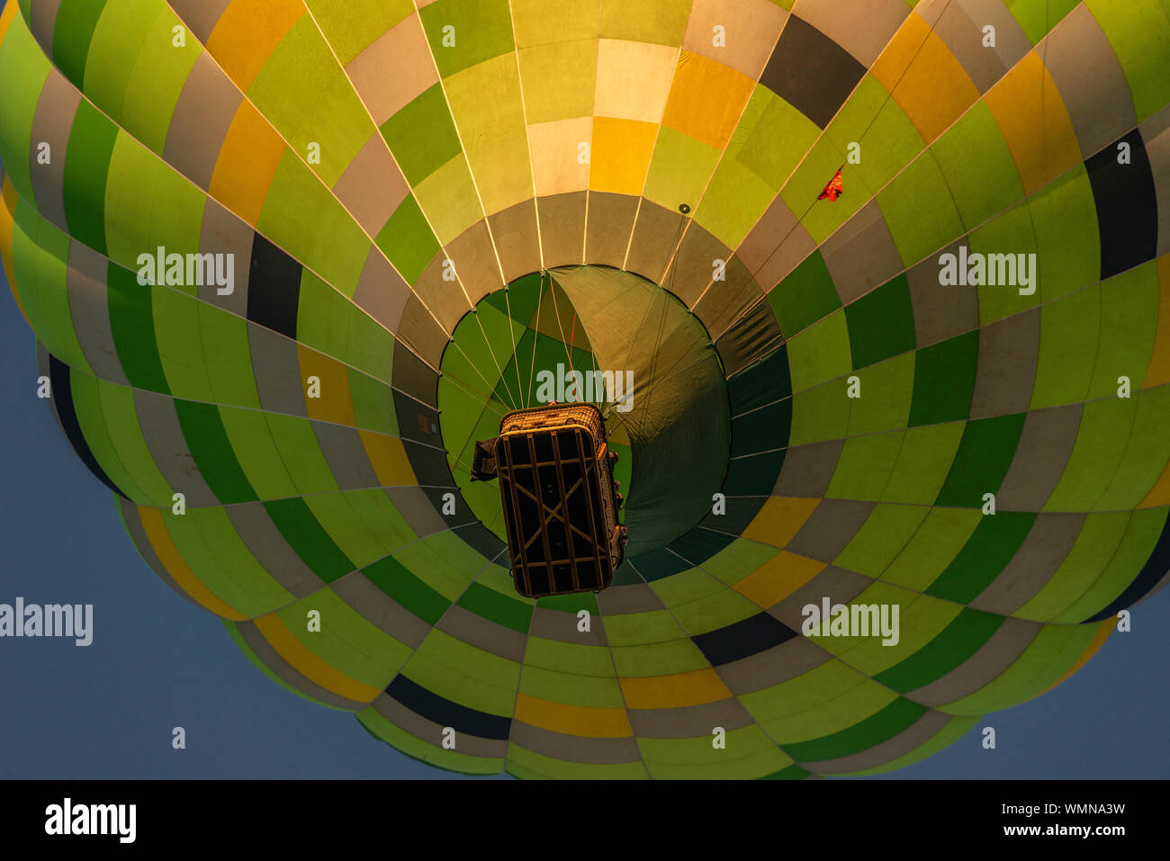 Large inflated balloon with passengers in basket, flying close overhead ...