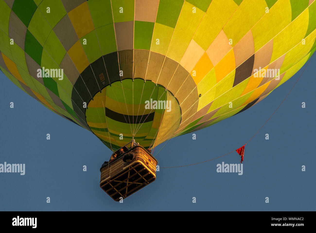 Large inflated balloon with passengers in basket, flying close overhead ...