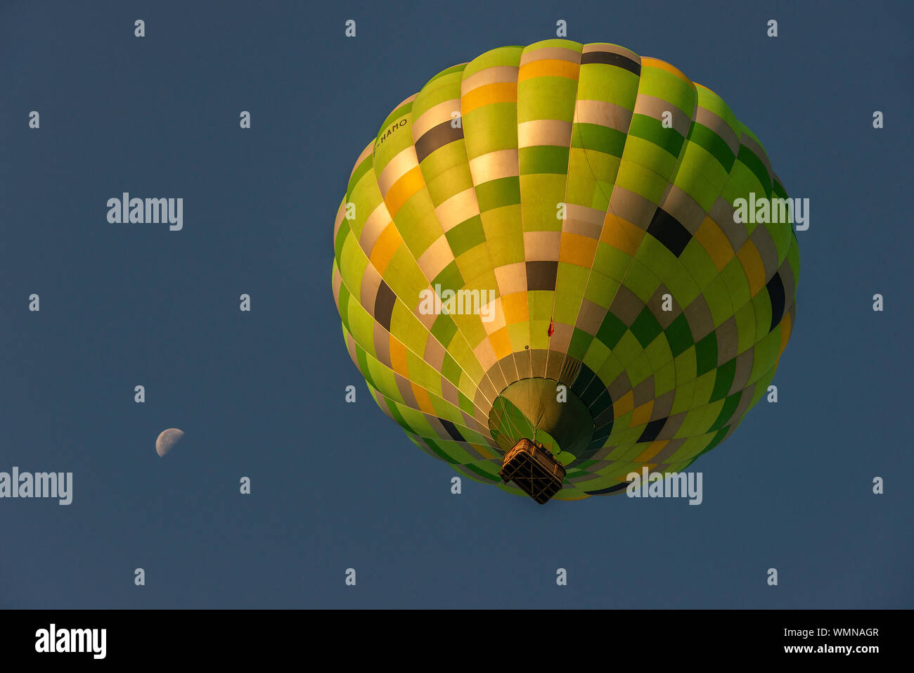 Large inflated balloon with passengers in basket, flying close overhead ...