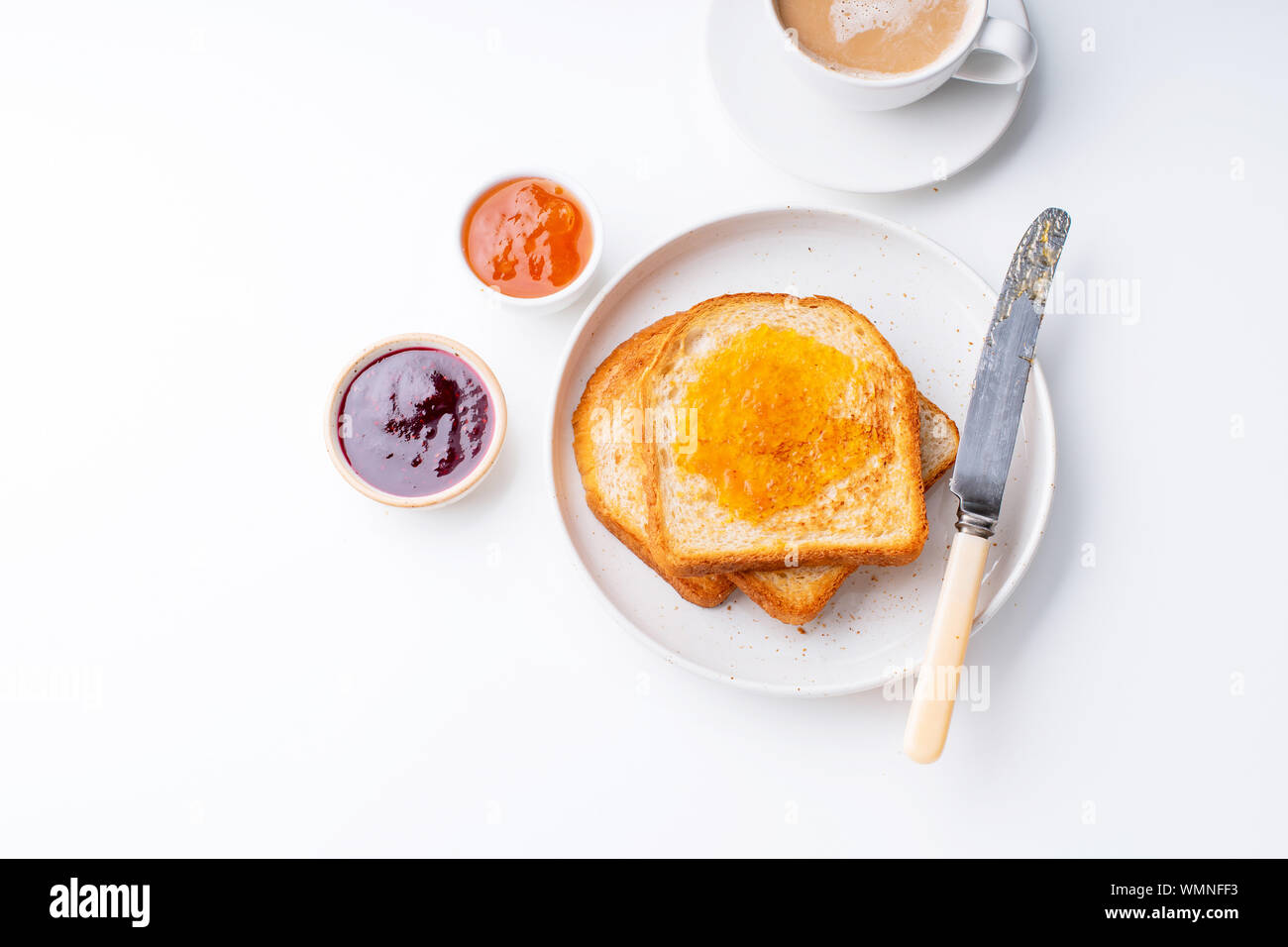 Morning toasts with butter and confiture on white table served with a ...