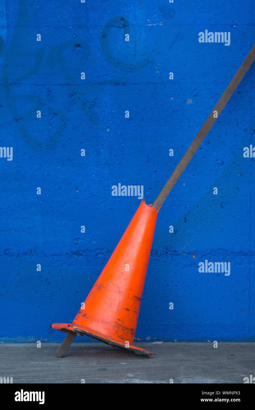 Broken Traffic Cone On Sidewalk Against Blue Wall Stock Photo - Alamy