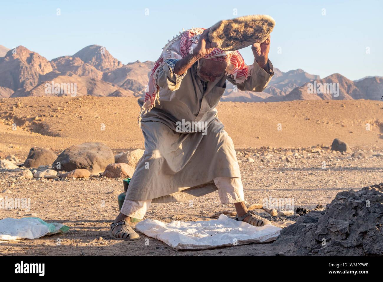 Bedouin baking bread in traditional open fire method using salt water ...