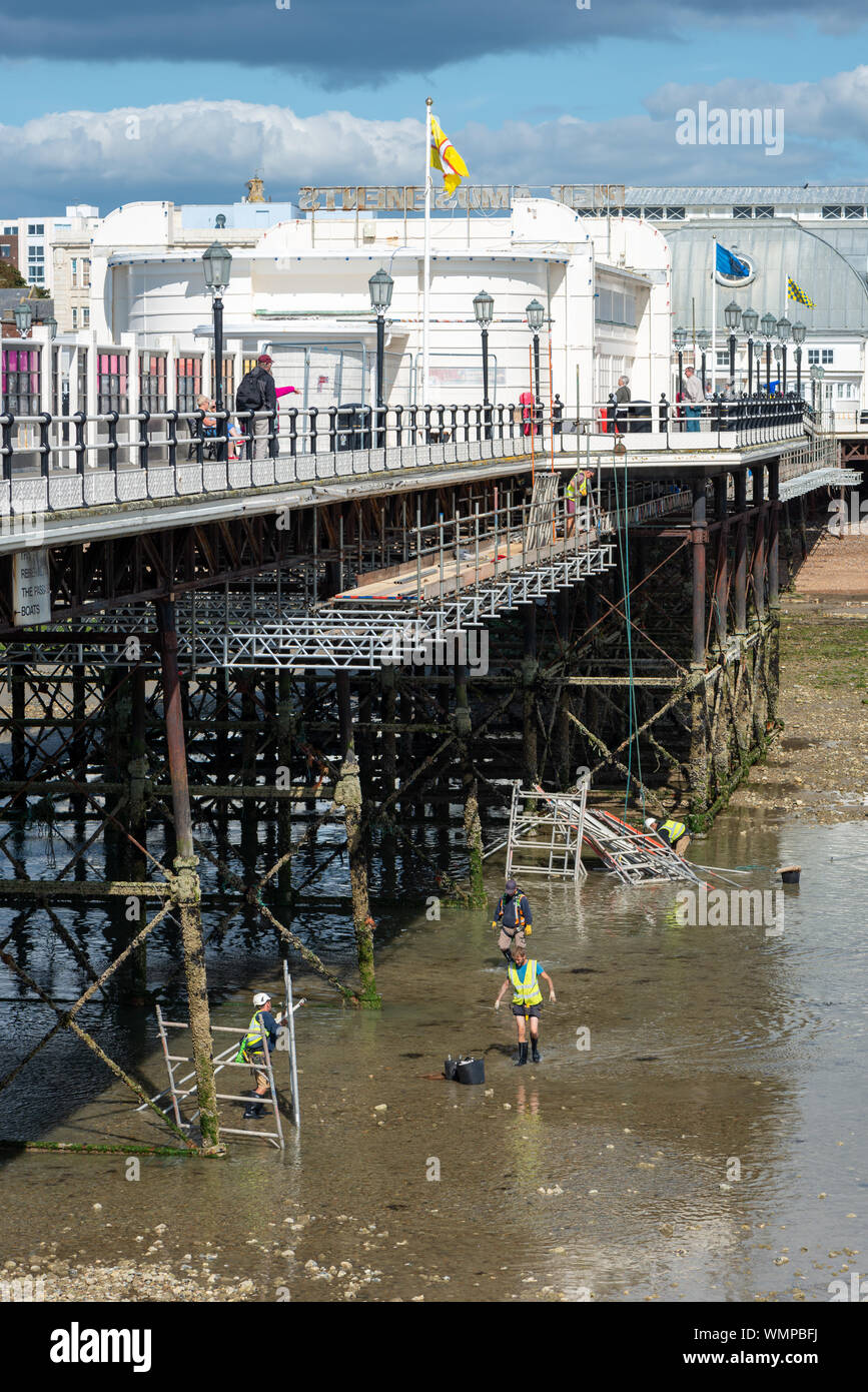 Workmen working during low tide under Worthing Pier in Worthing, West ...