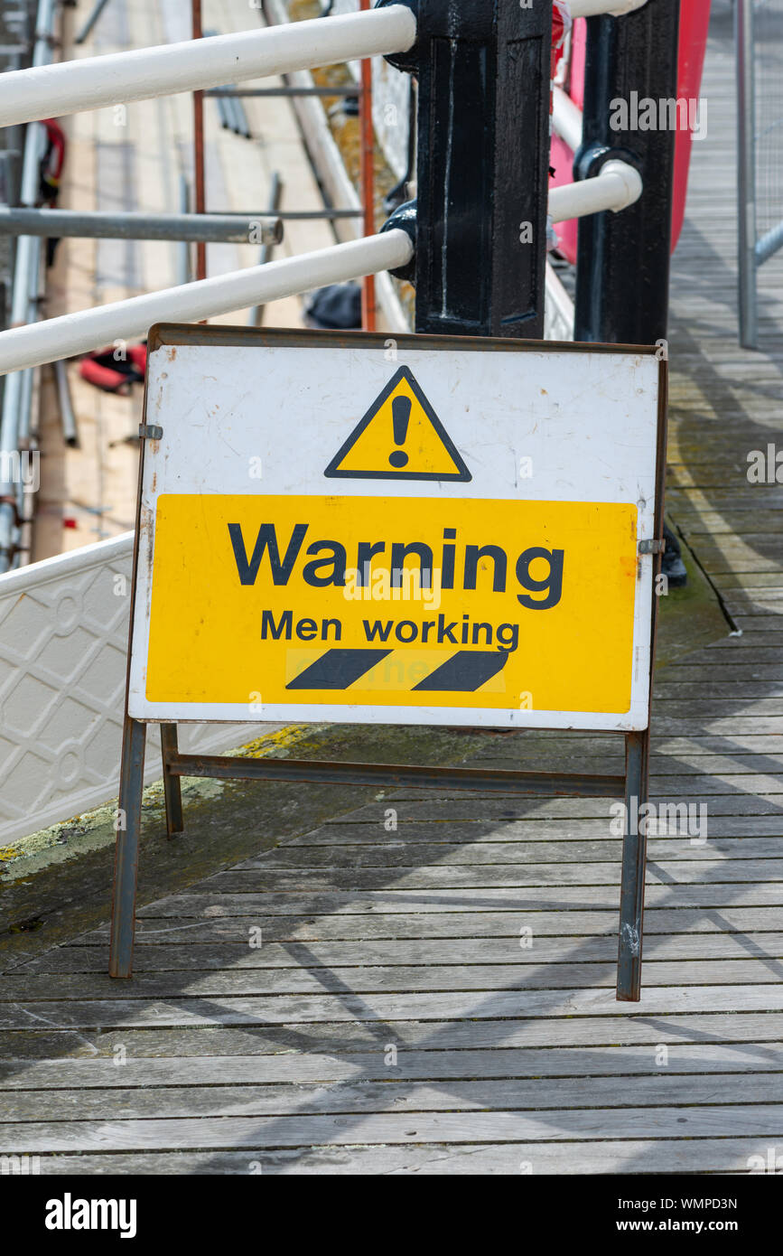 A yellow warning men working sign Stock Photo - Alamy