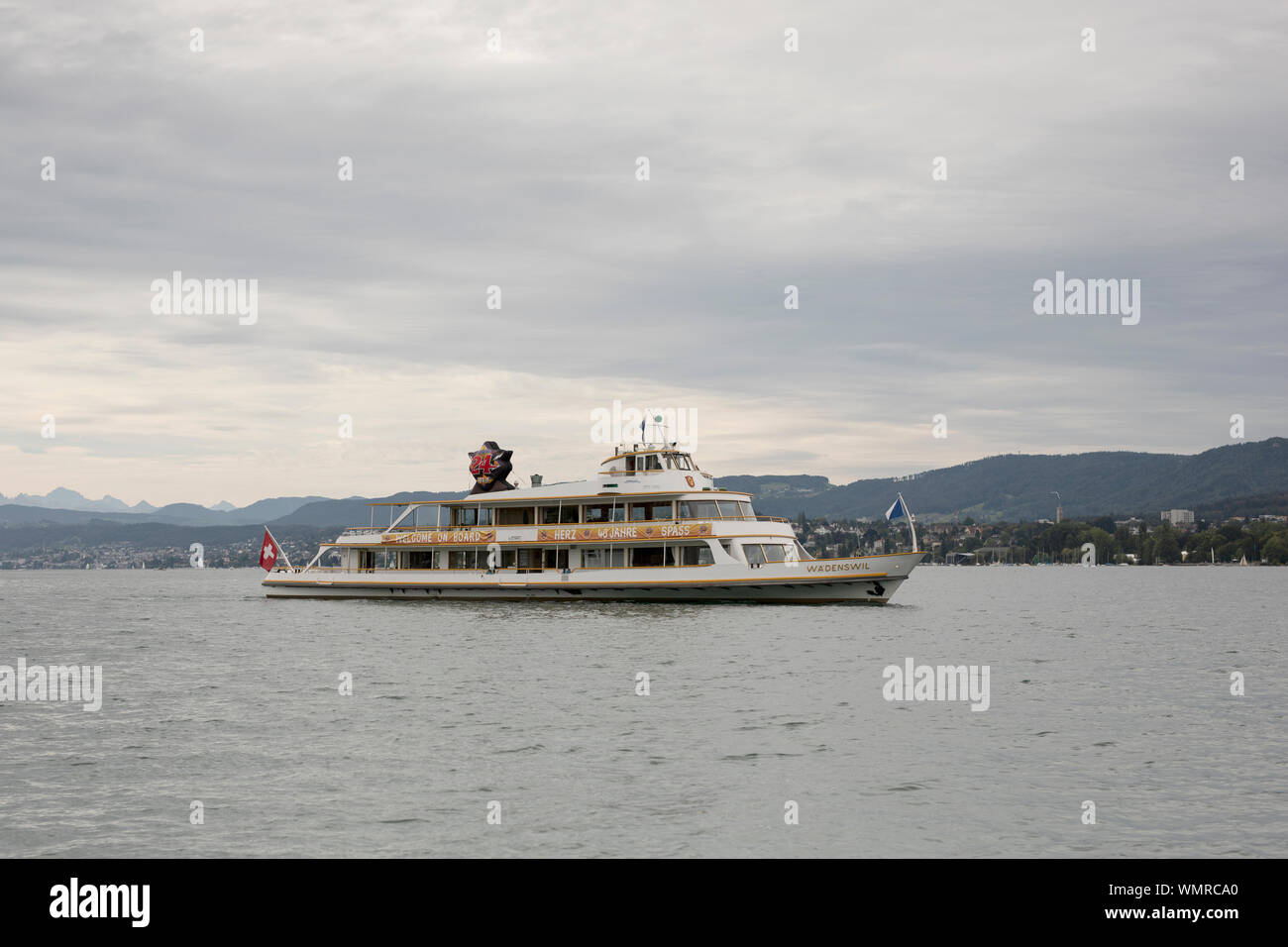 A tour boat pulls into the harbor at Lake Zurich on a cloudy day in ...