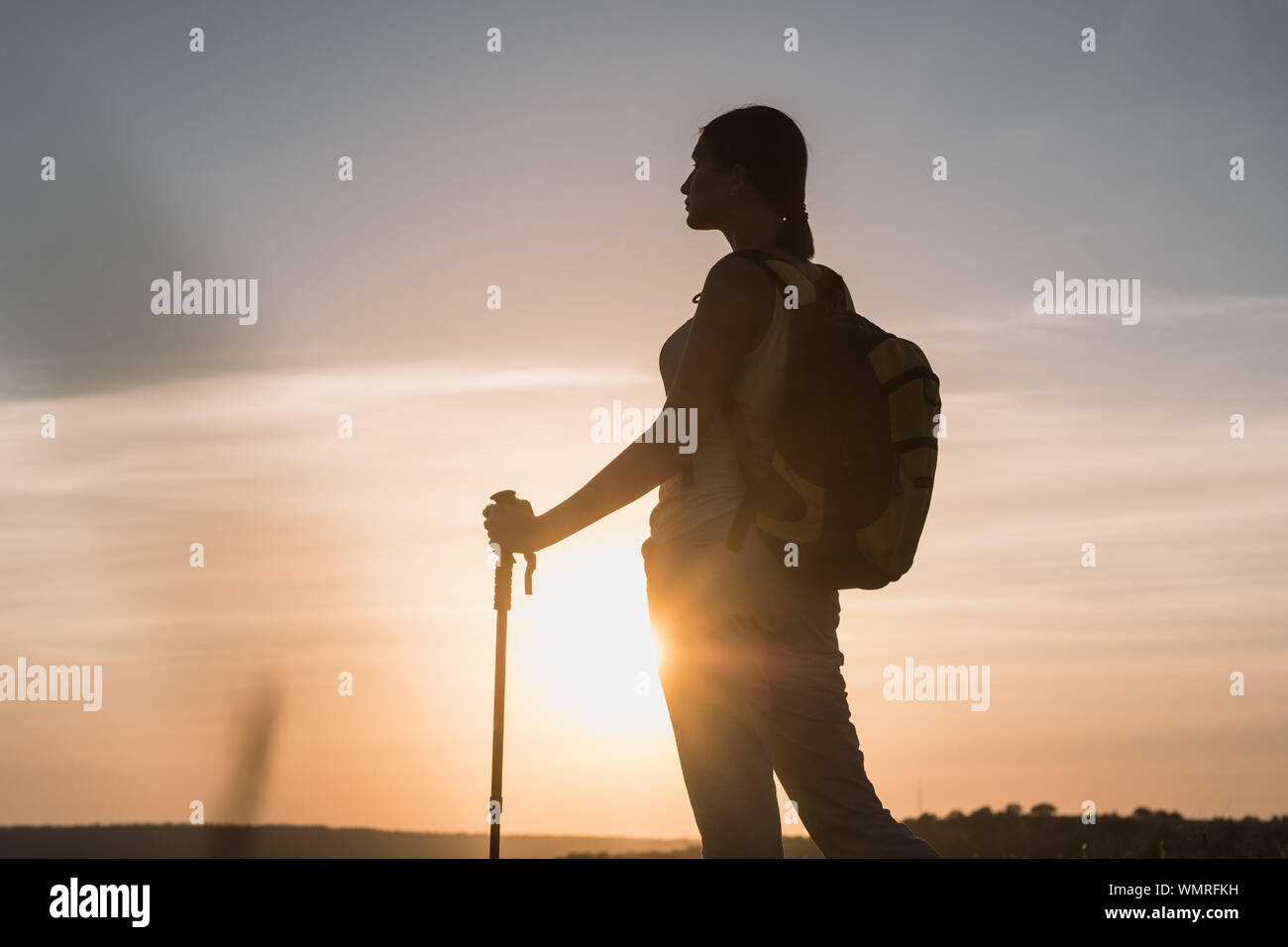 Silhouette hiker woman tracking with backpack and trekking pole, sunset ...