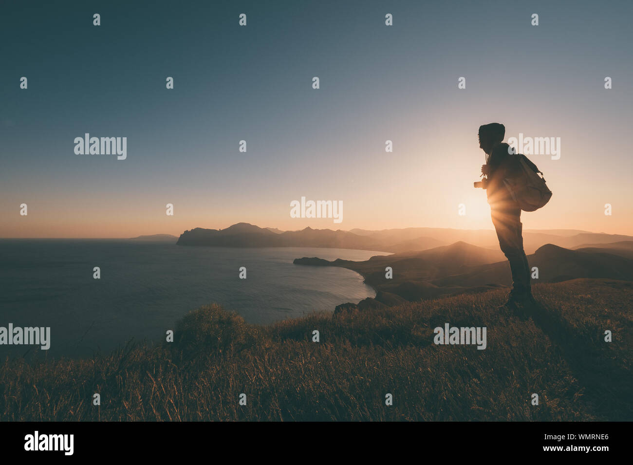 Young standing man with backpack. Hiker on the stone on the seashore at ...