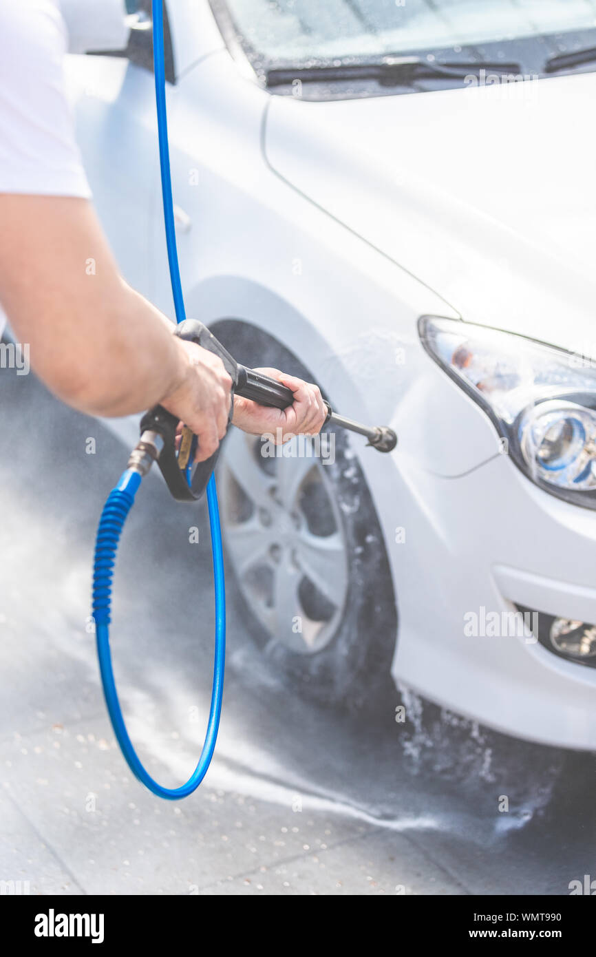 Close up of man washing his car with pressurized water in car wash ...