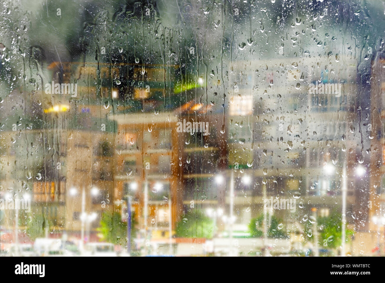 Abstract background of night city street raining through the window ...