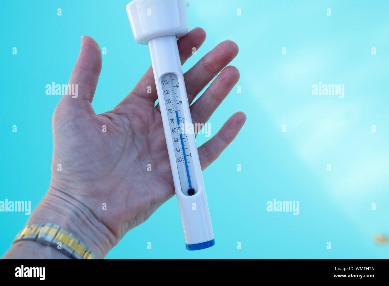 Checking the temperature of the swimming pool water with a thermometer ...