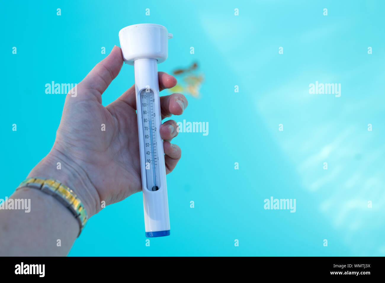 Checking the temperature of the swimming pool water with a thermometer ...