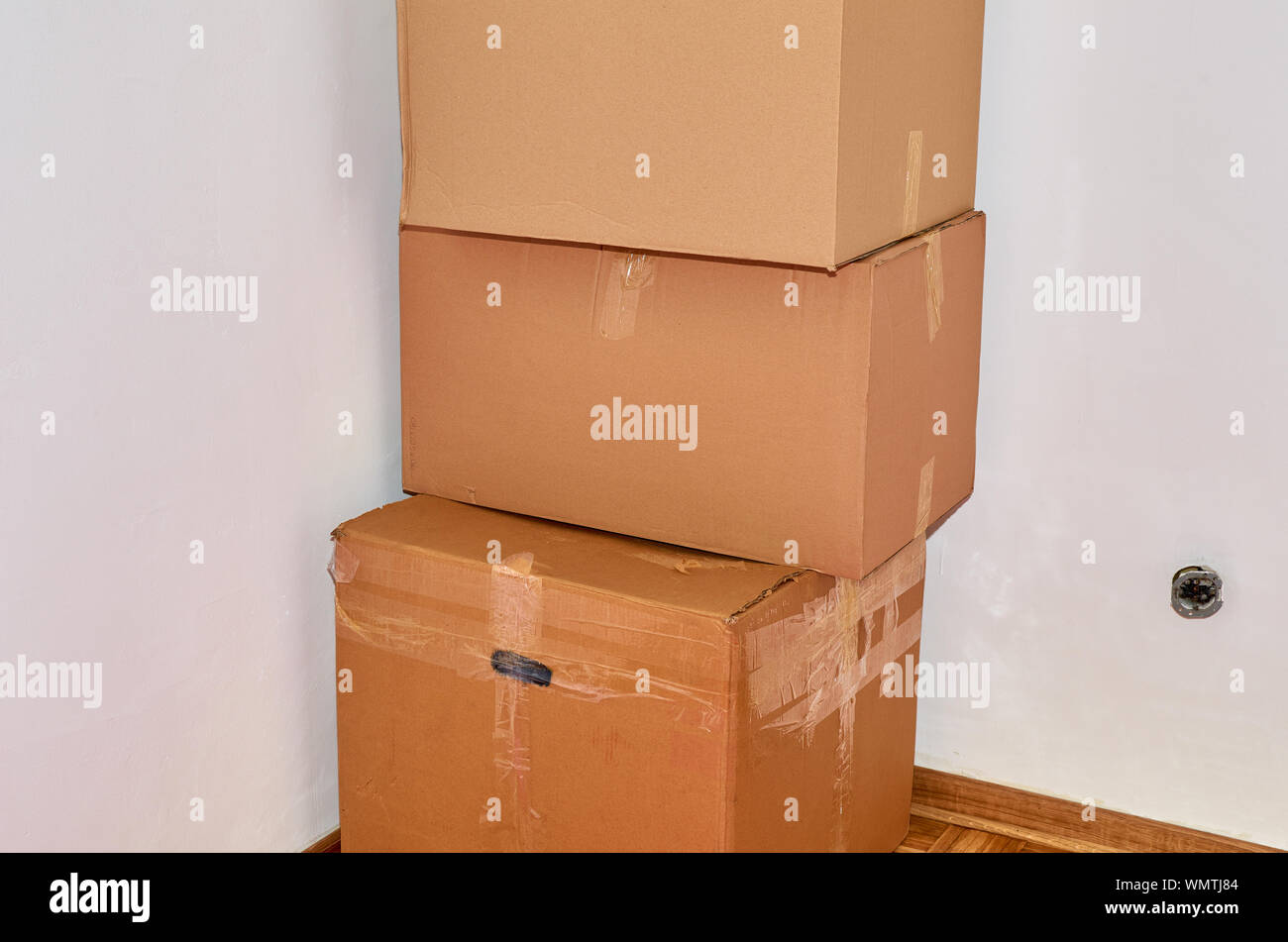 Three cardboard moving boxes in a corner of a room Stock Photo - Alamy