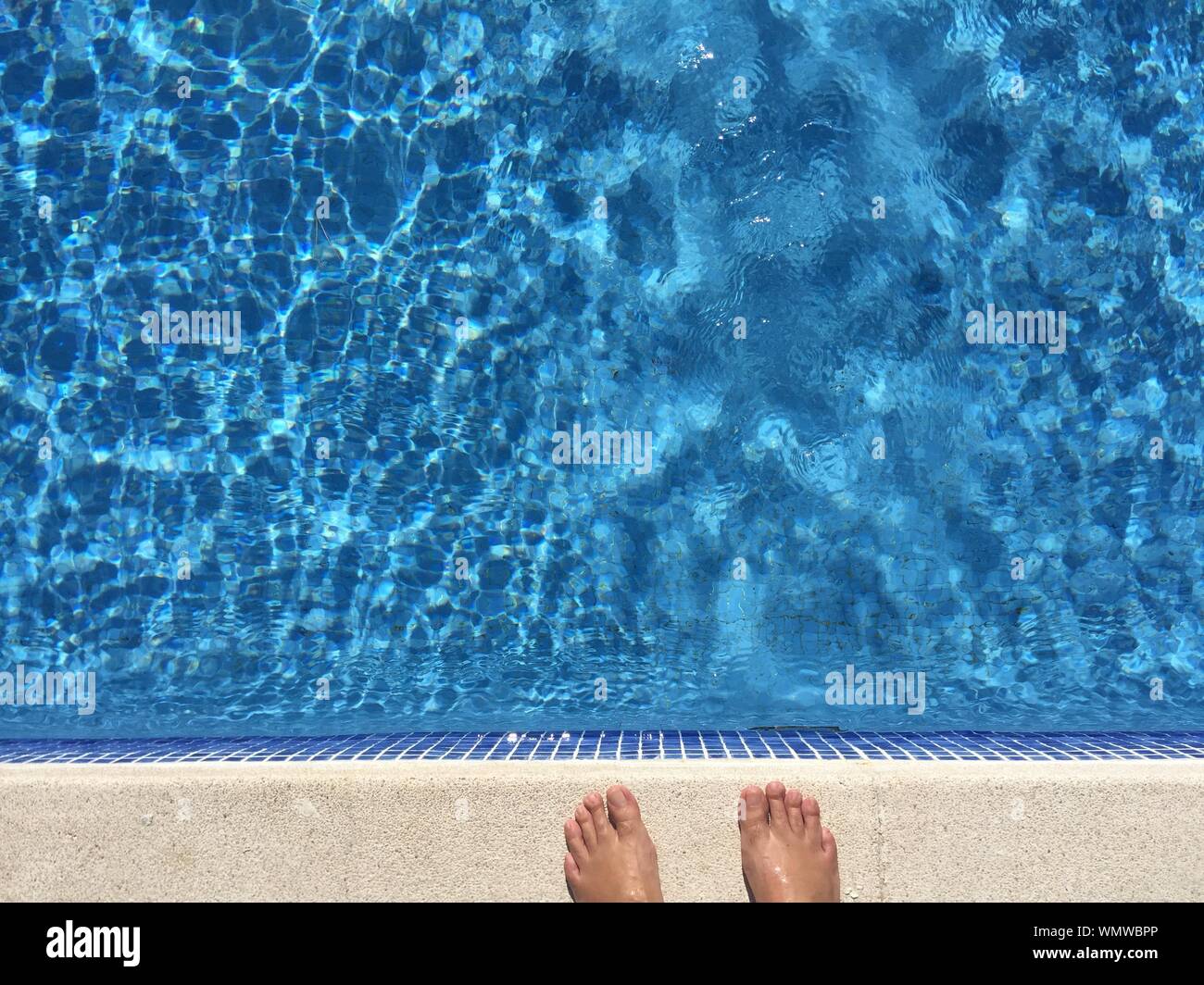 Low Section Of Person Standing By Swimming Pool Stock Photo - Alamy