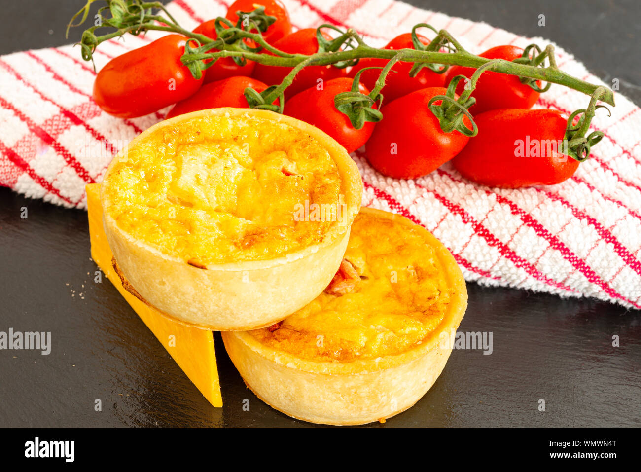 Two Small quiche served on a black slate tray fresh out of the oven ...