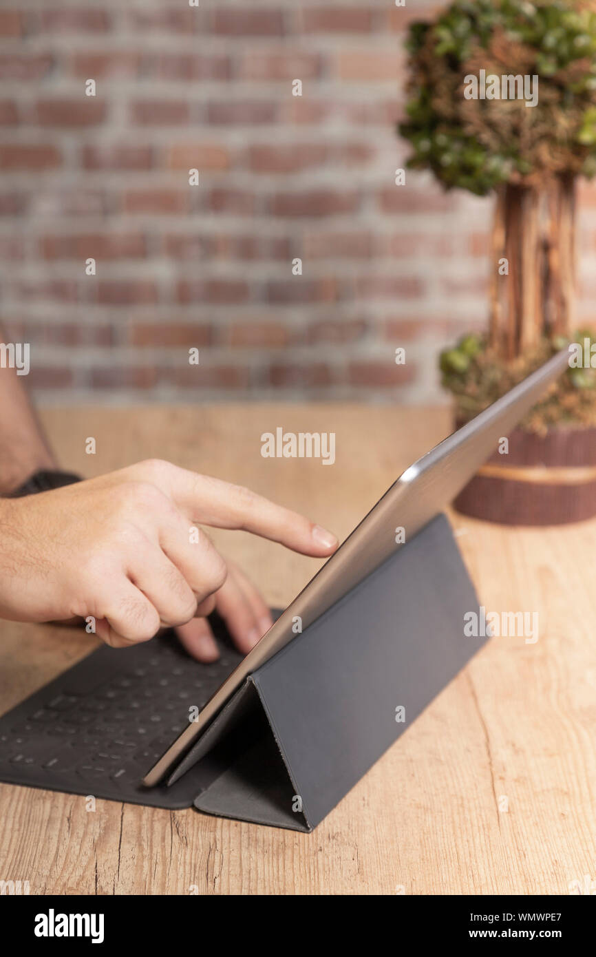 Man using a tablet computer to work, on a wooden table, in front of a ...