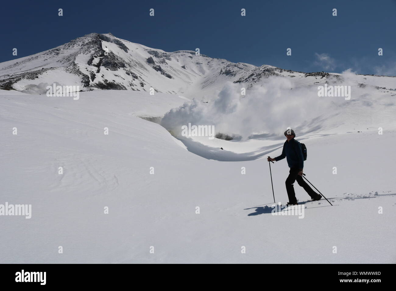 Man snow shoeing in front of steaming active volcano Stock Photo - Alamy