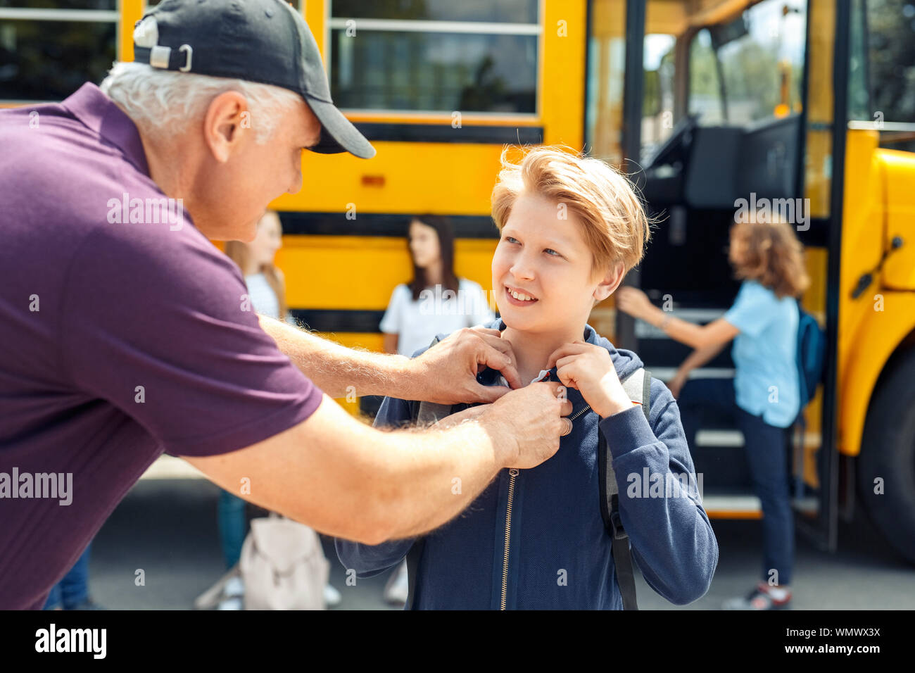 Father seeing off his son to school bus helping with grooming smiling ...