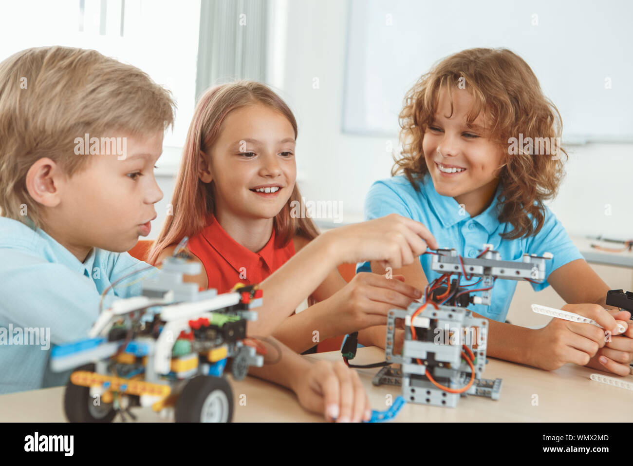 Children having robotics class sitting at table making robots smiling ...