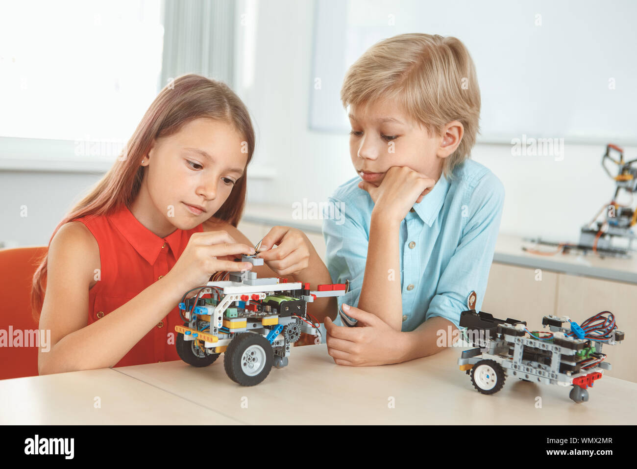 Children brother and sister having robotics class sitting at table ...