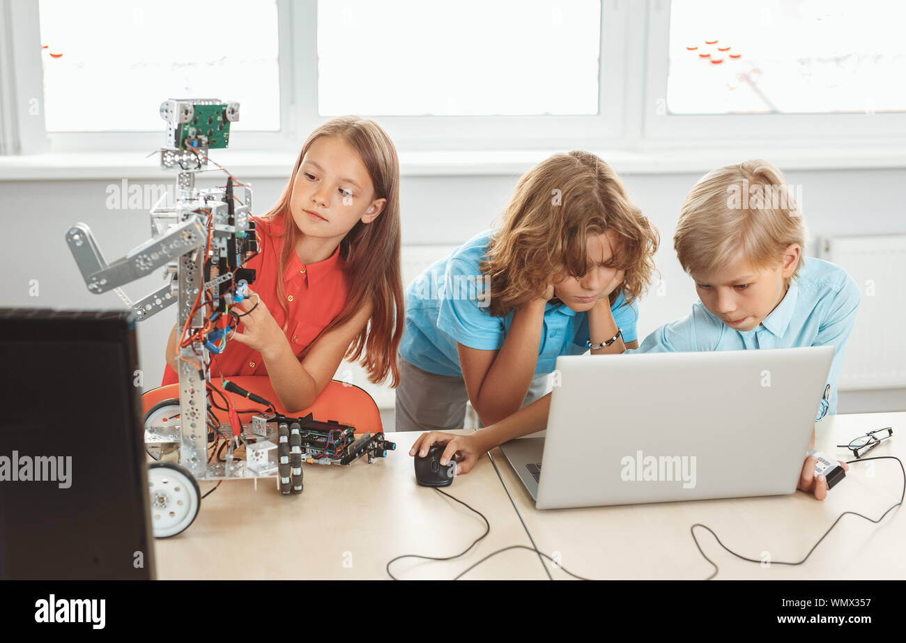 Children having robotics class making robot browsing internet on laptop ...