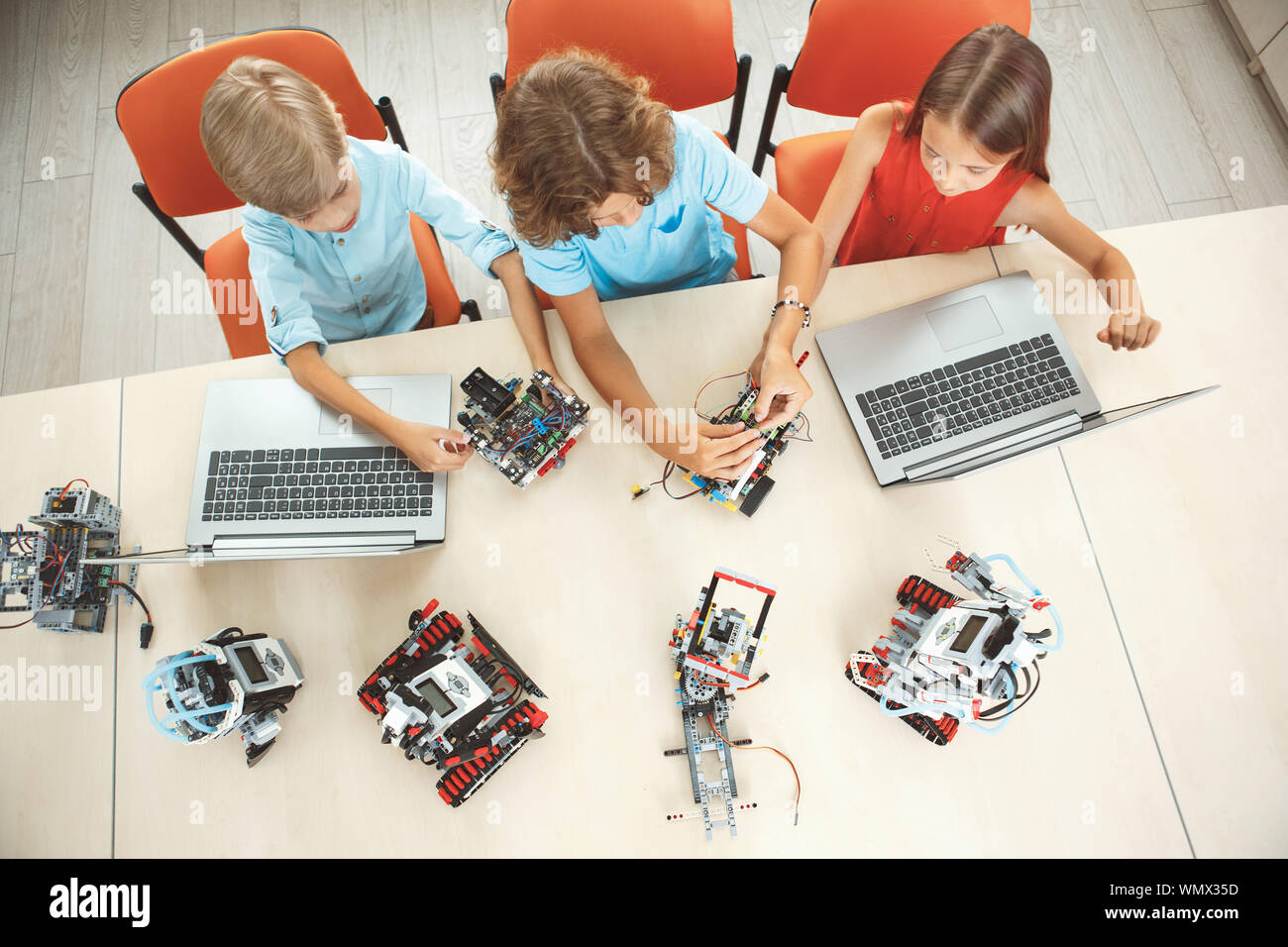 Children having robotics class sitting at table making robots using ...