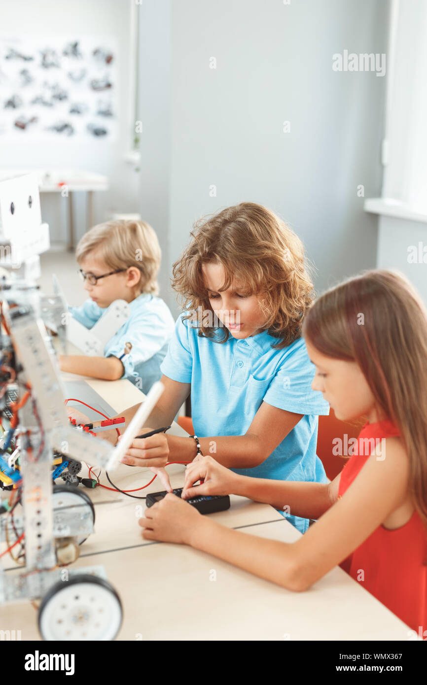 Children having robotics class sitting at table making robots welding ...