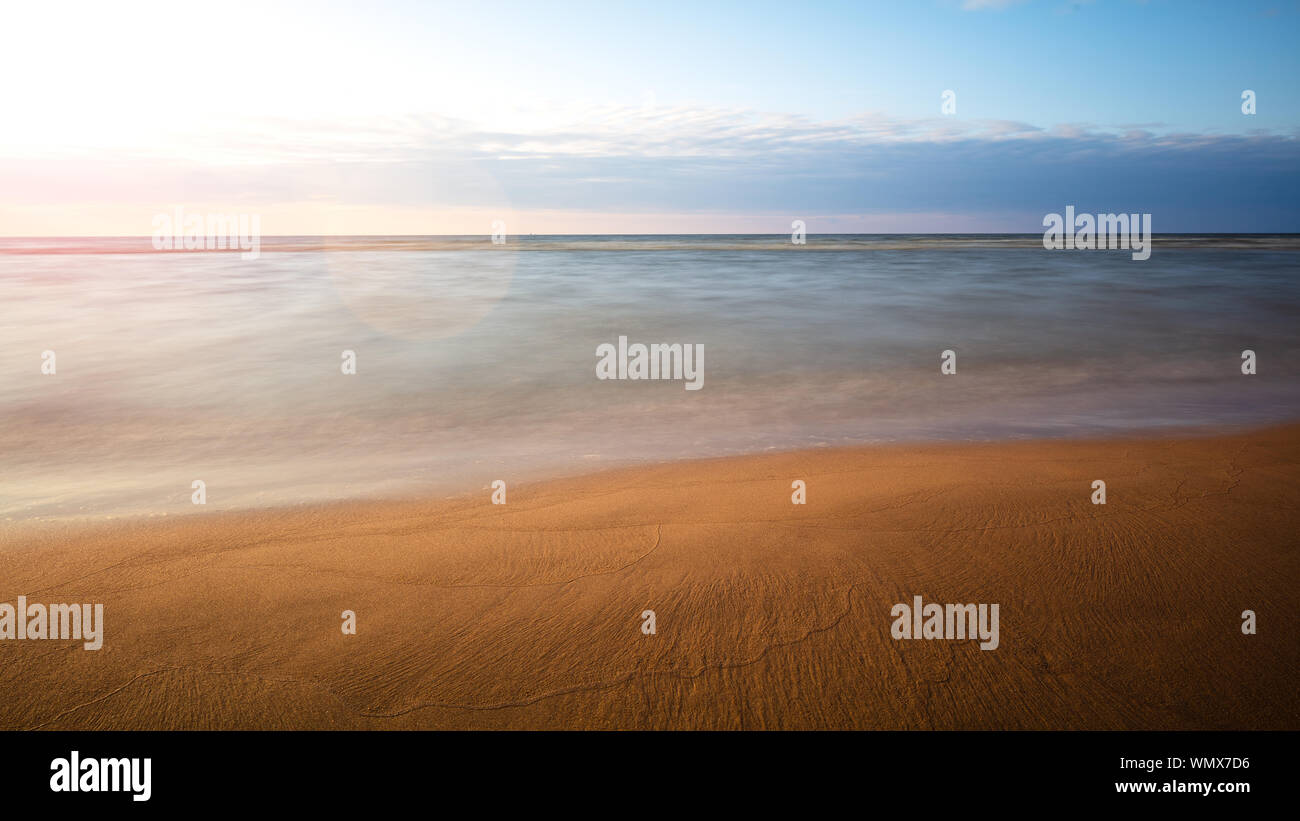 Long exposure of colourful sunset on the beach with sky motion for ...