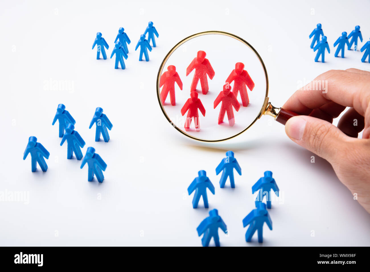 Hand Holding Magnifying Glass Over Red Human Figures Surround By Blue ...