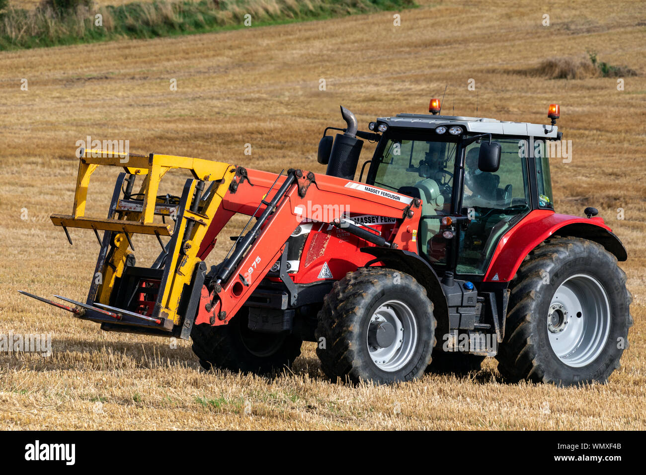 Agriculture - a tractor collecting bales of hay following the ...