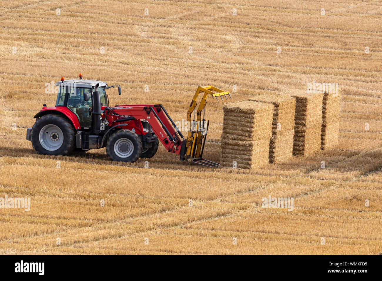 Agriculture - a tractor collecting bales of hay following the ...