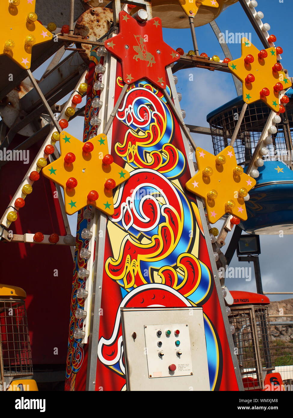 A photograph of a small funfair ferris wheel shot in daylight on a out ...